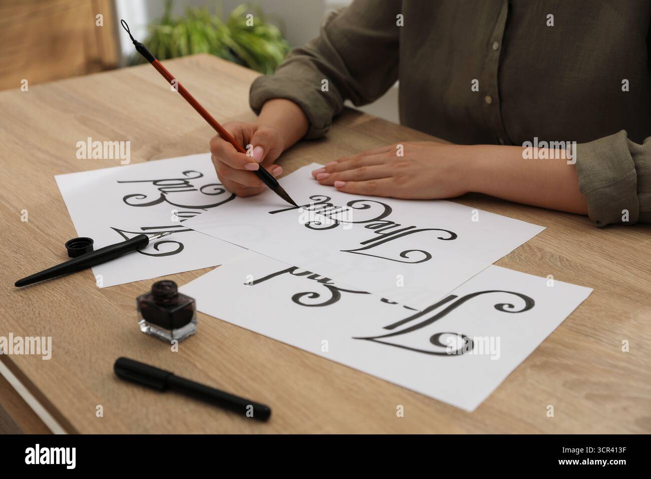 Calligraphy. Woman with brush writing words The End on sheet of paper ...