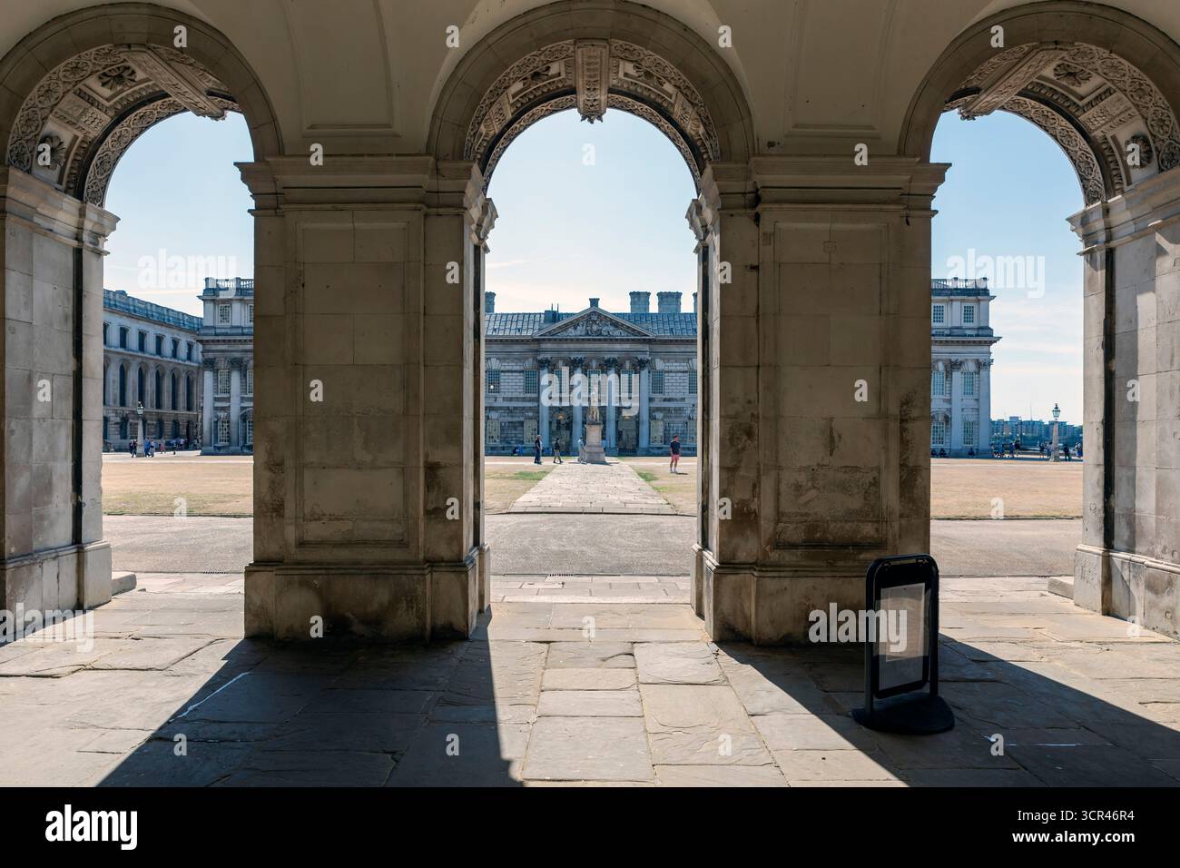 Historic archways framing a classical building in a sunlit courtyard ...