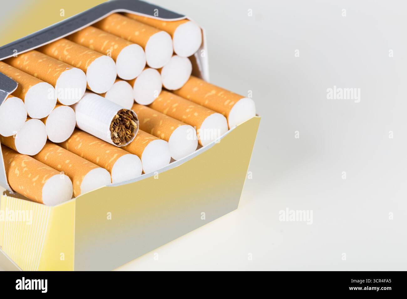 Open cigarette pack displaying neatly arranged cigarettes and one half ...