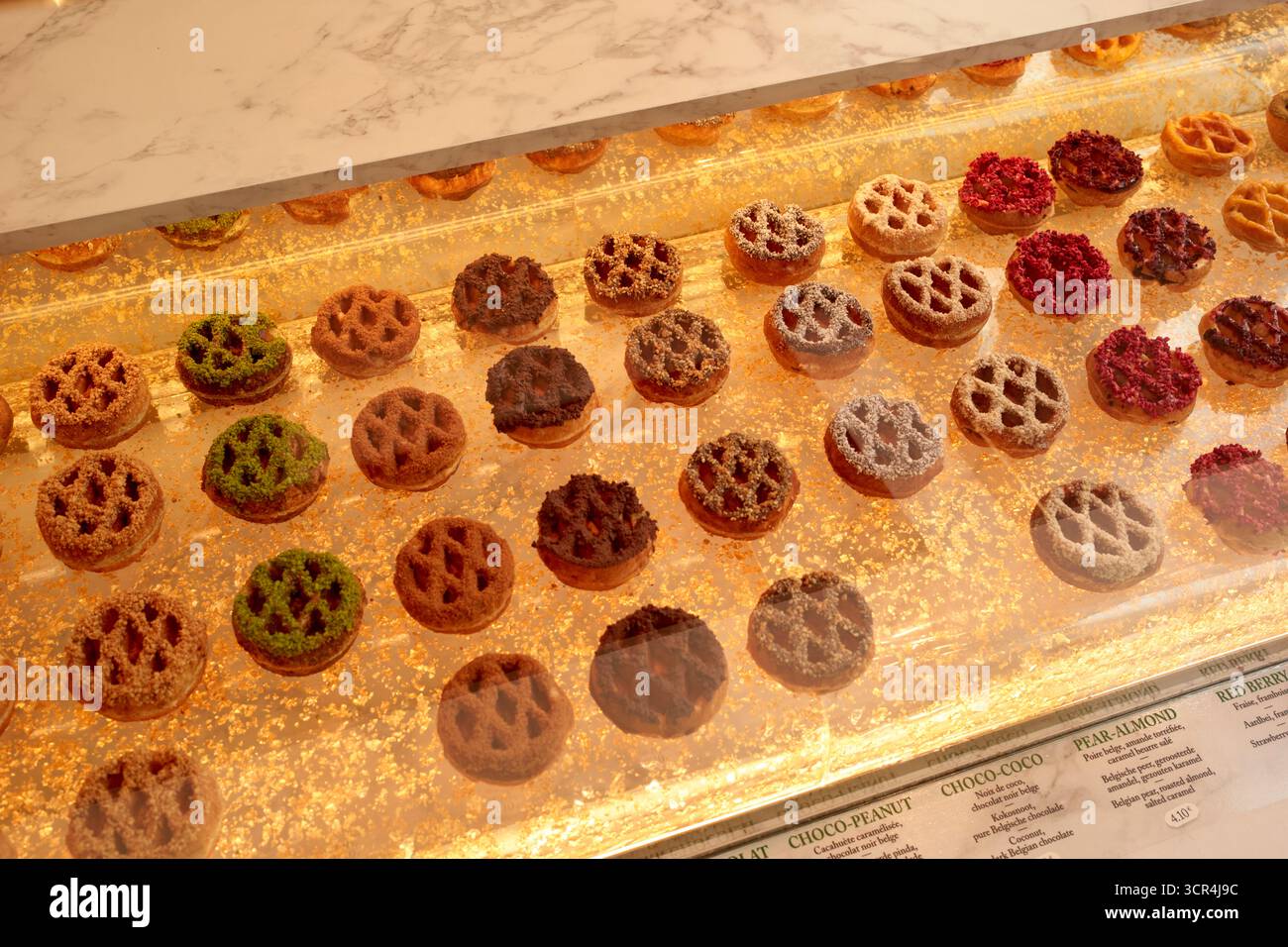 Display of assorted mini tarts on a marble countertop in a warm bakery ...