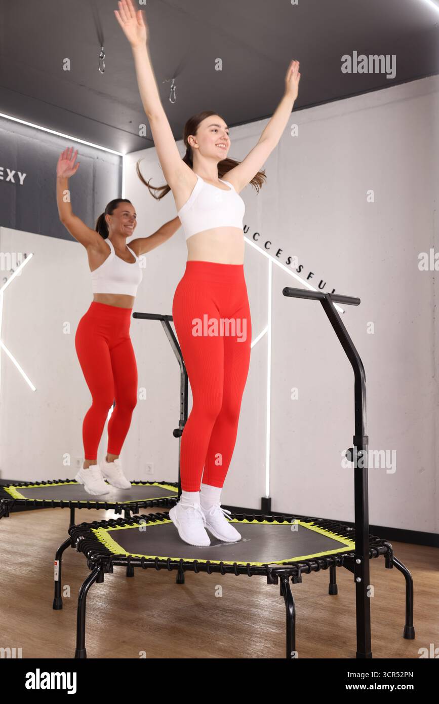 Smiling women jumping on mini exercise trampolines in fitness studio ...