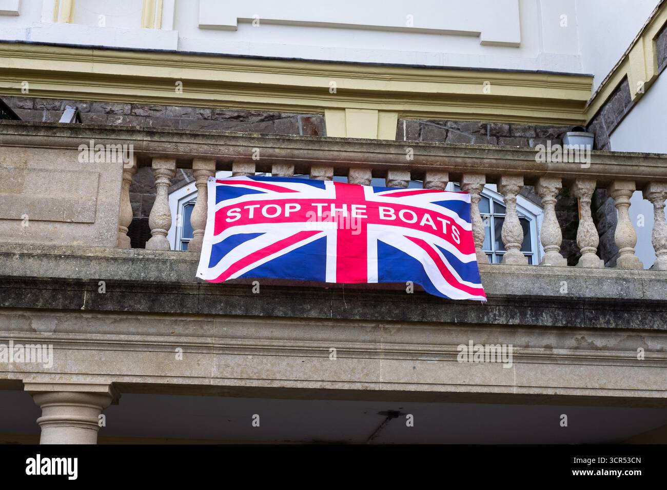 A "Stop the Boats" banner hangs from a building's balcony, expressing a ...