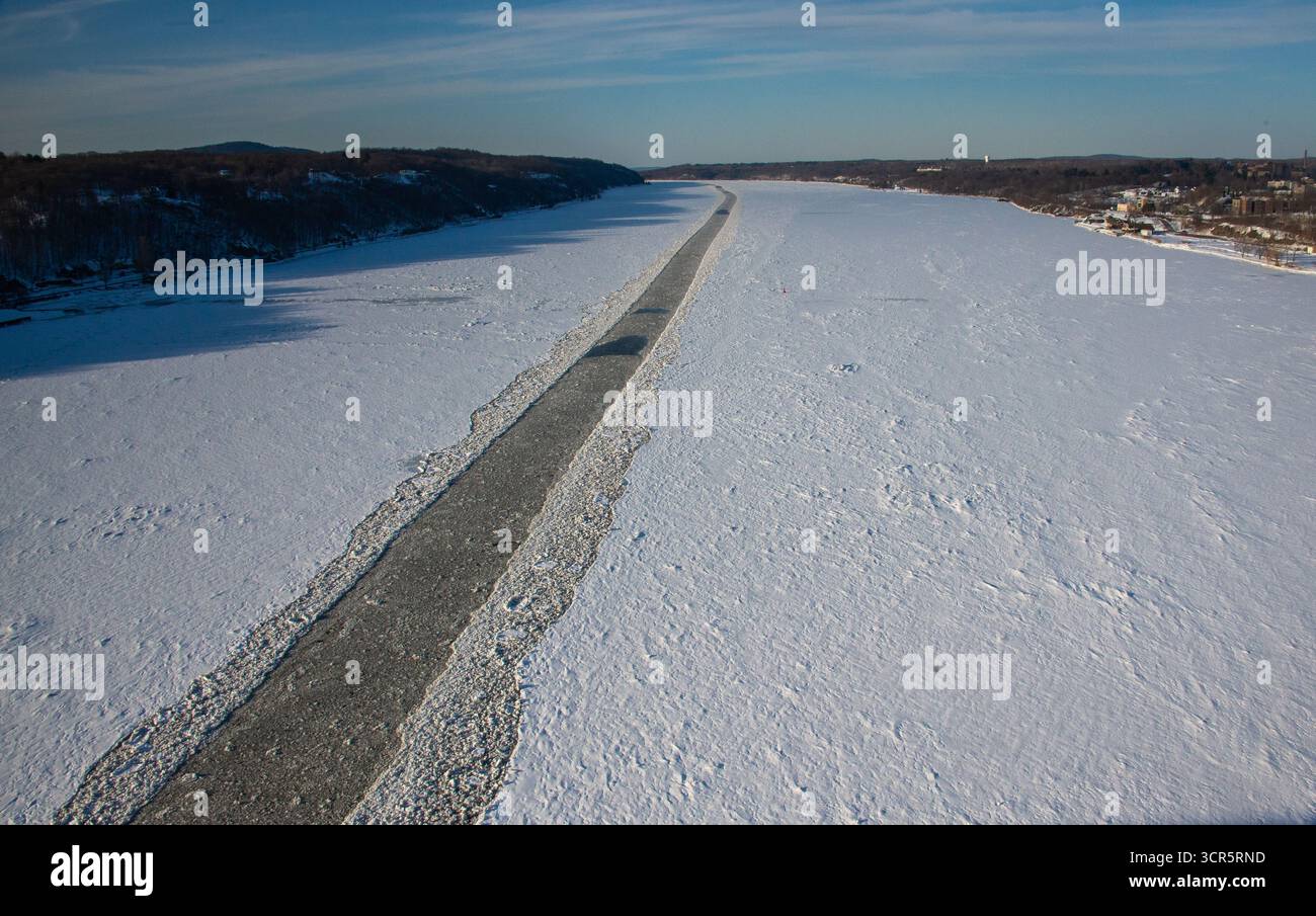 Aerial view of a frozen river, a stark white expanse cleaved by a ...
