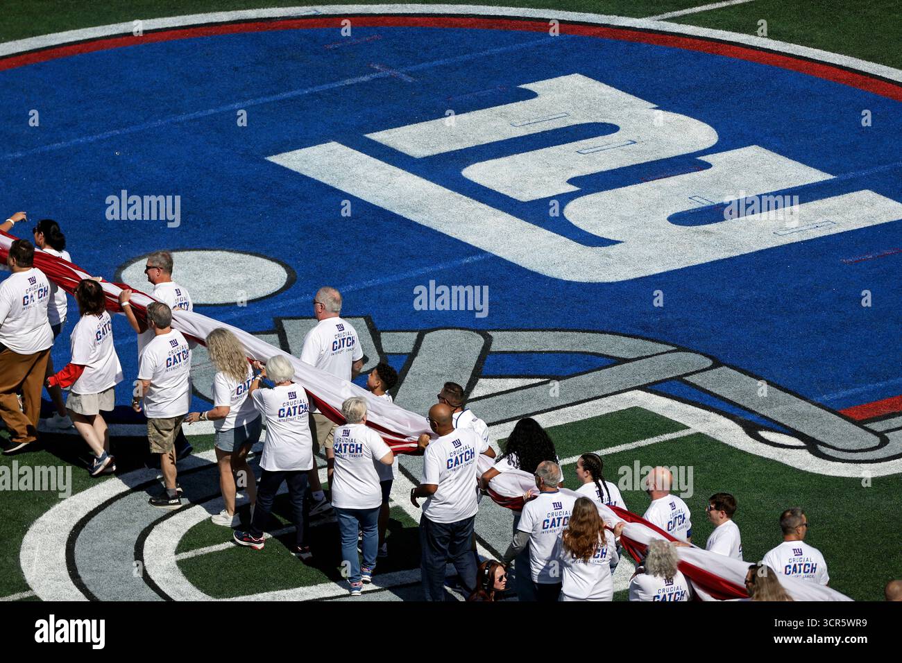 Volunteers carry of a large American Flag following the national anthem ...