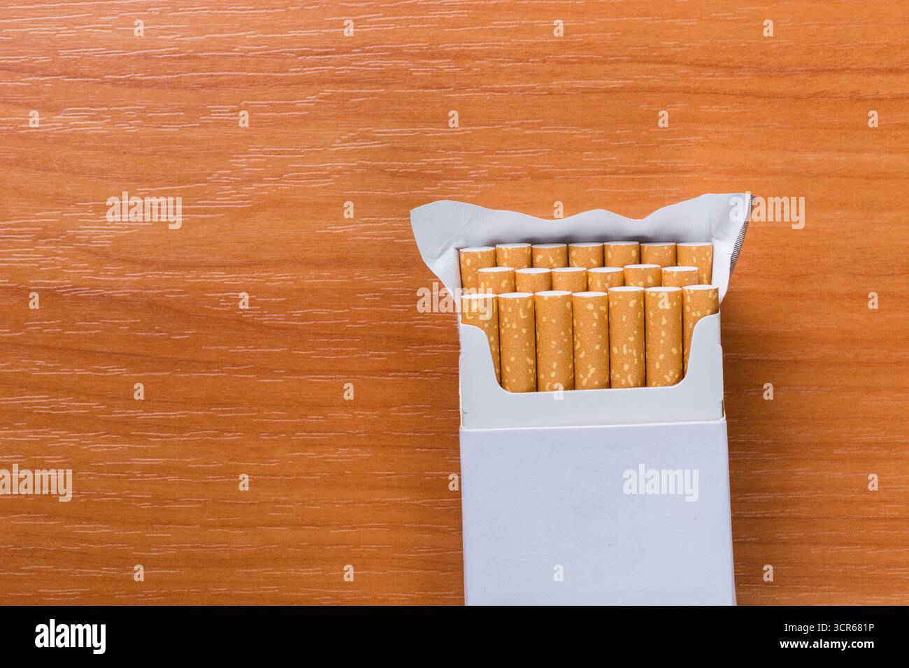 Cigarettes in an open pack resting on a wooden surface with a simple ...