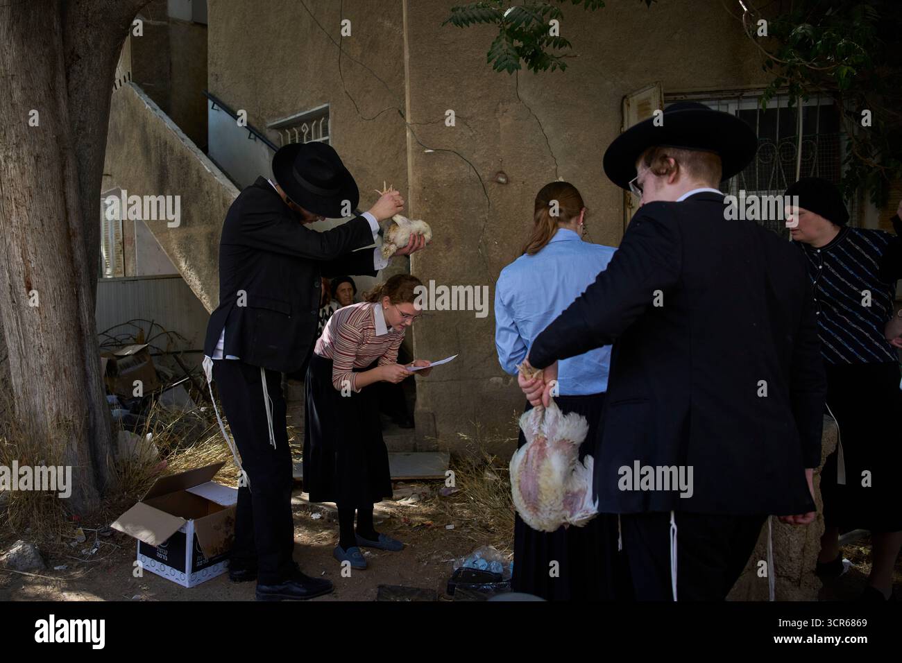 An ultra-Orthodox Jewish man swings a chicken over a woman head in ...