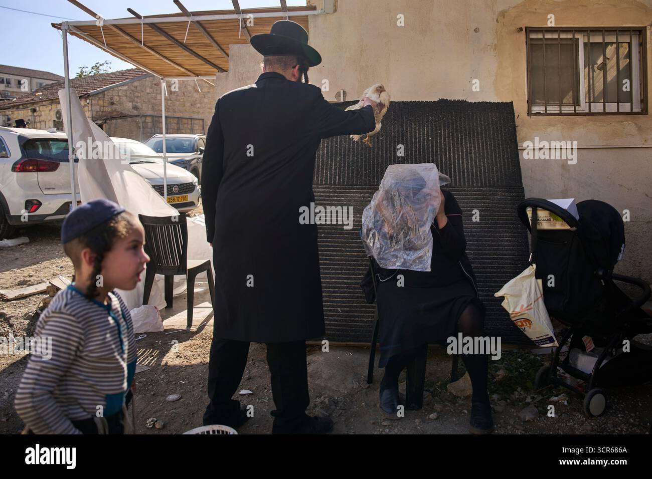 An ultra-Orthodox Jewish man swings a chicken over a woman head in ...