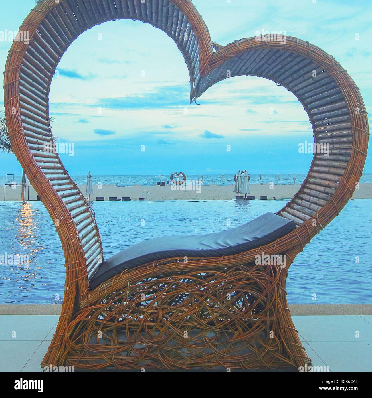 Rattan heart chair near infinity pool with tropical beach view in ...