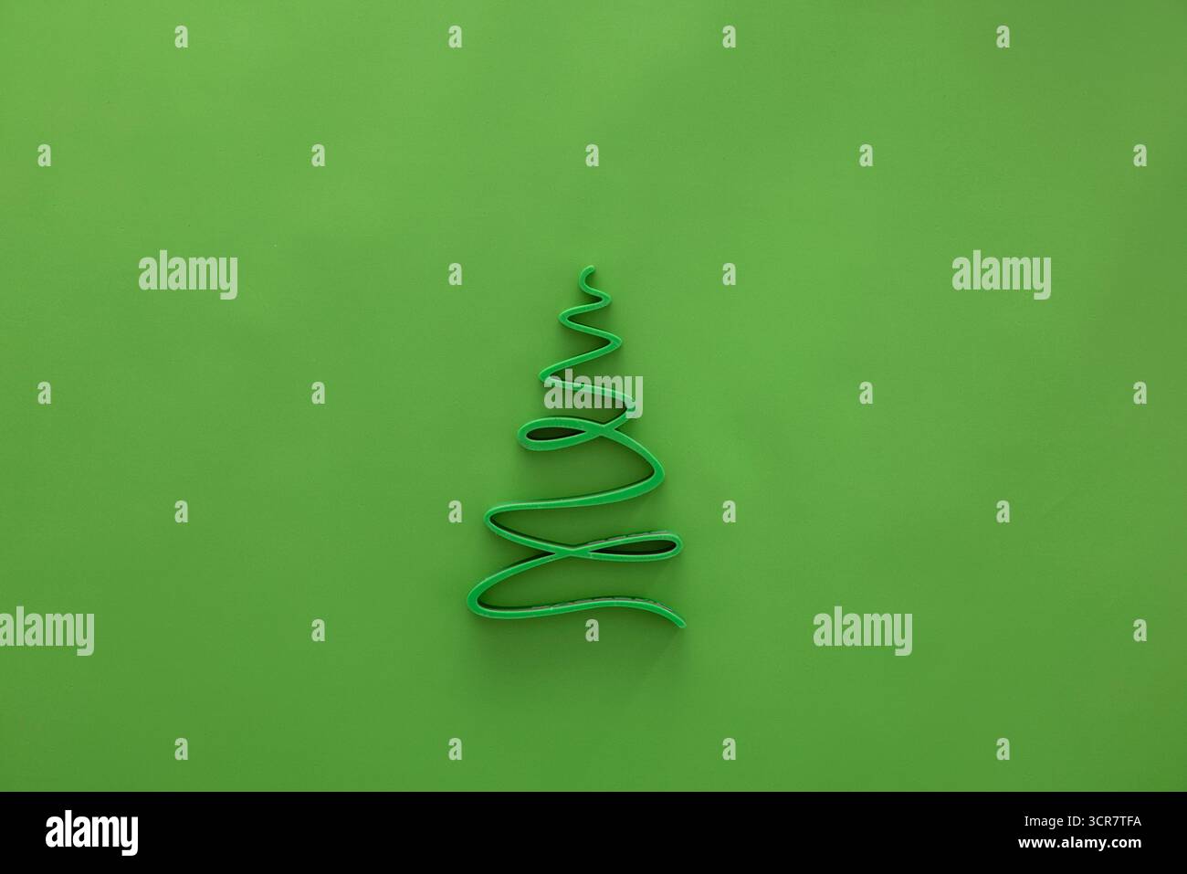 A simple green Christmas tree outline made of wire on a bright green ...