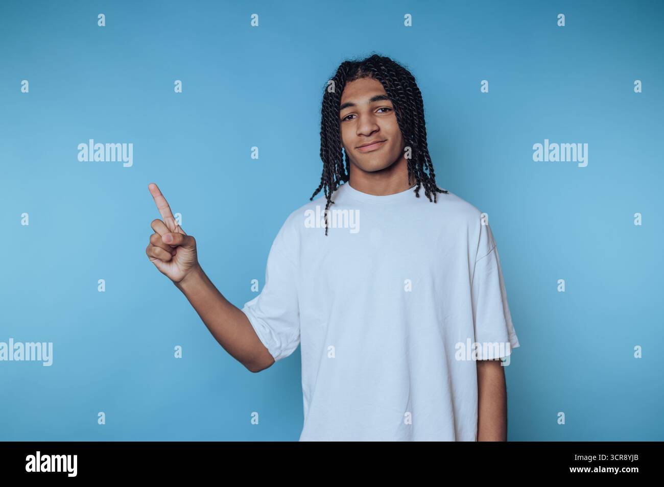 Teen gestures positively while standing against a solid blue background ...