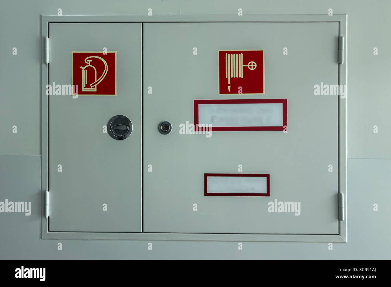 A white cabinet is mounted on the wall, labeled with fire safety ...