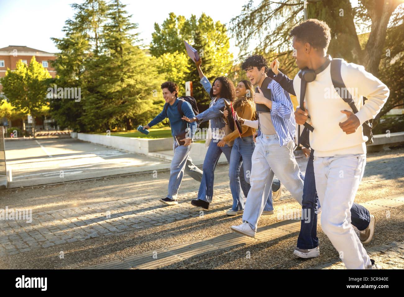 Group of diverse university students with backpacks running across ...