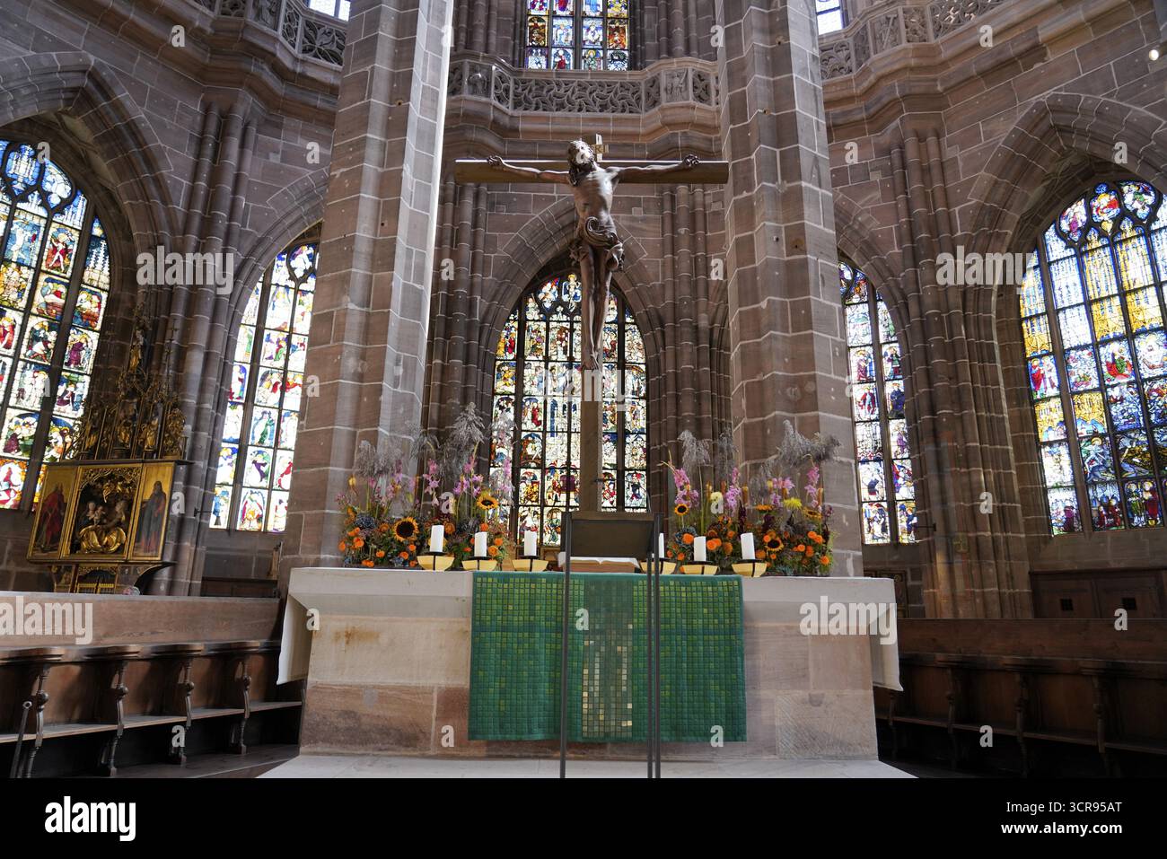 Church altar with cross and colourful stained glass windows depicting ...