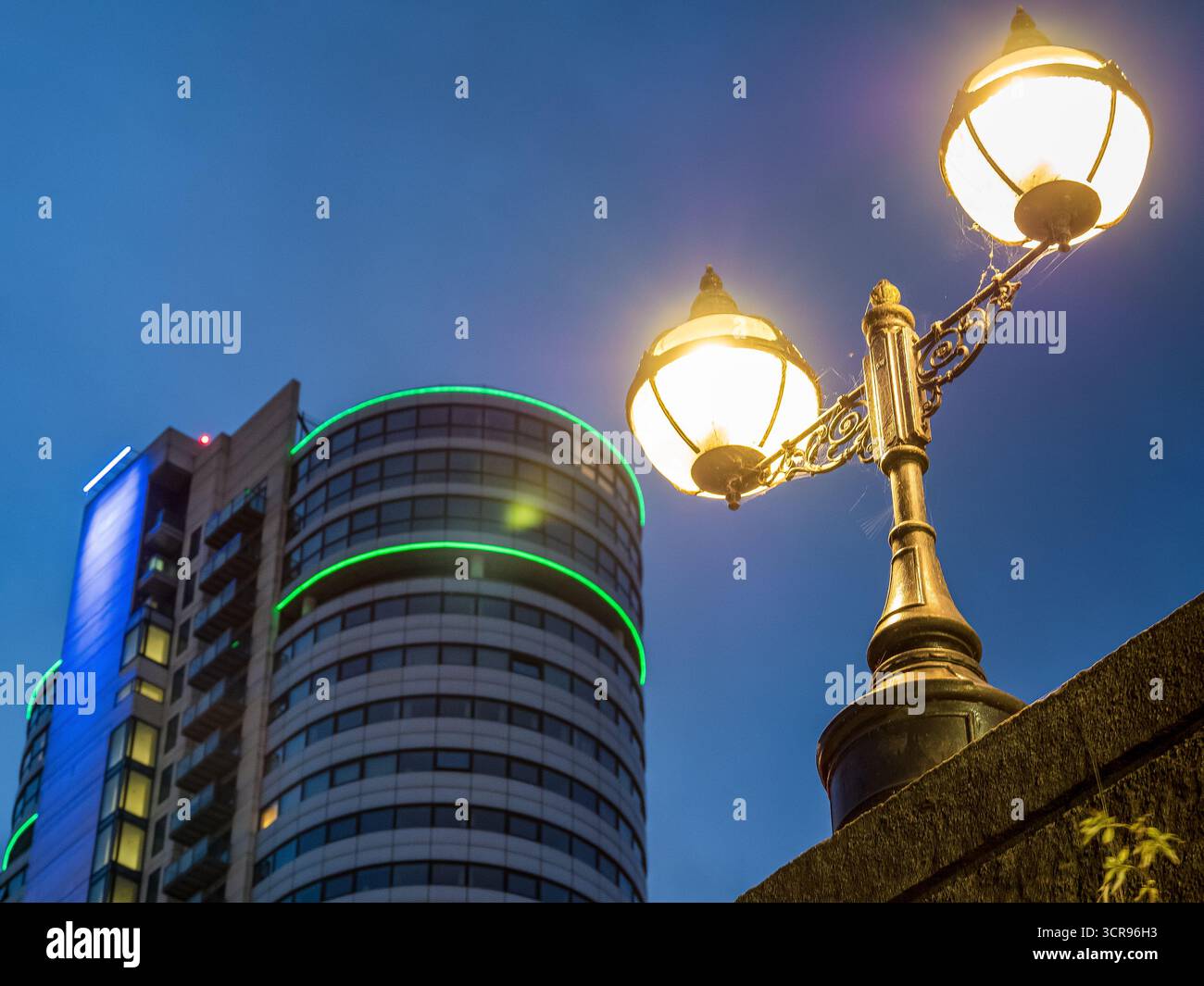 Traditional double headed street lamp glowing at twilight with ...