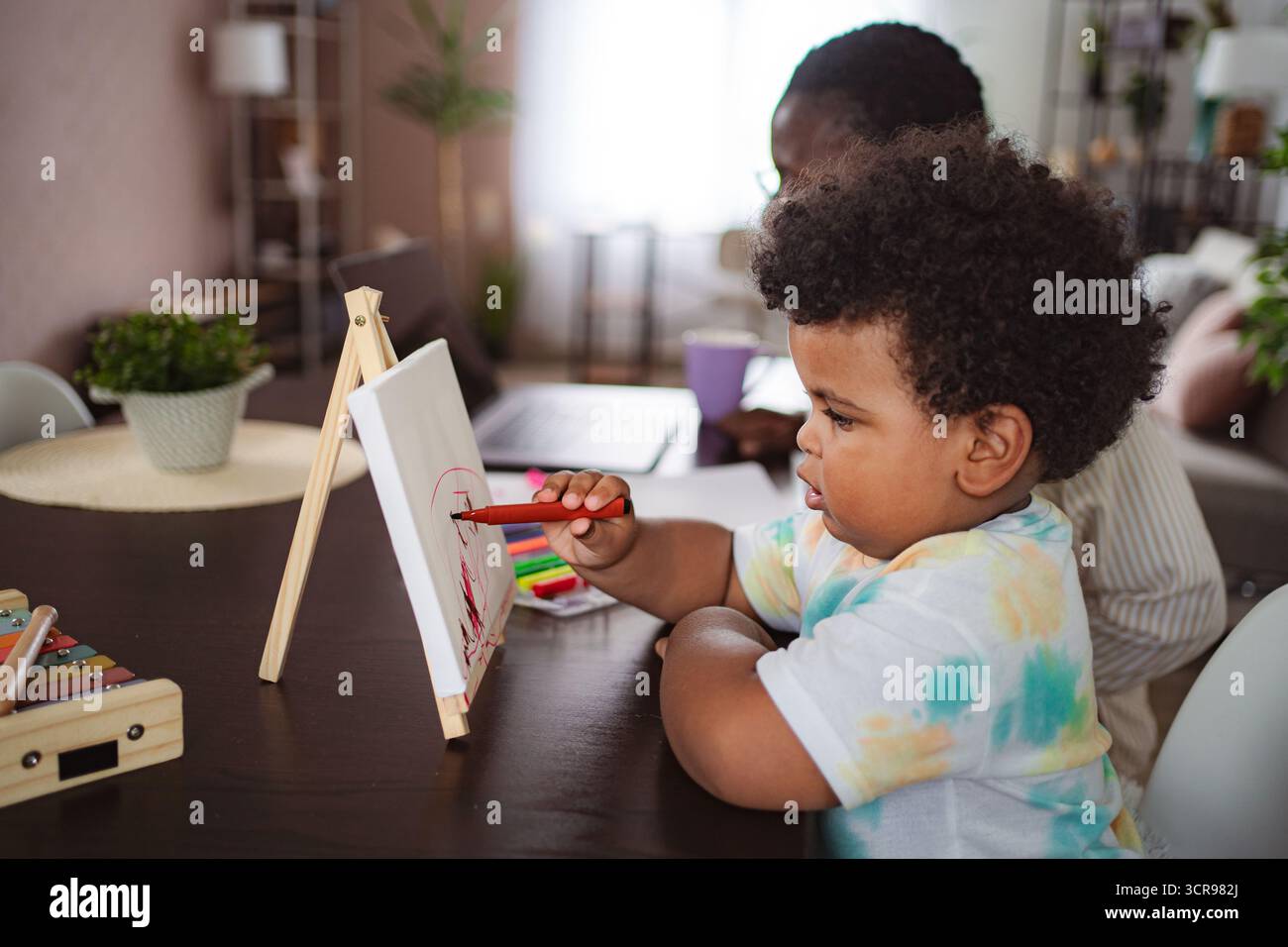 African american toddler drawing on easel at home Stock Photo - Alamy