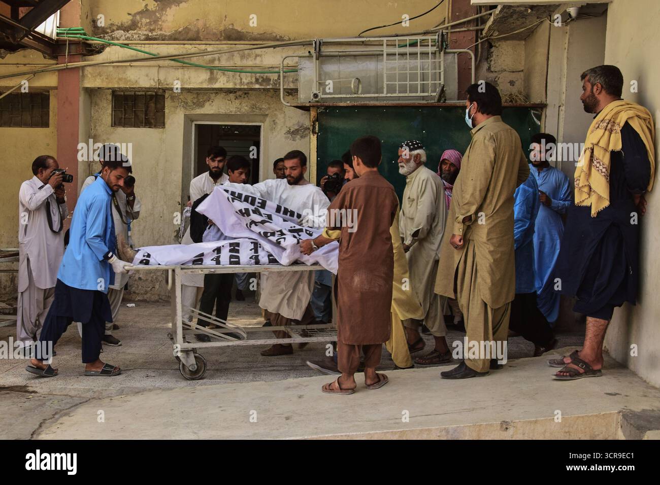 Rescue workers and volunteers transport the dead body of a victim of a ...