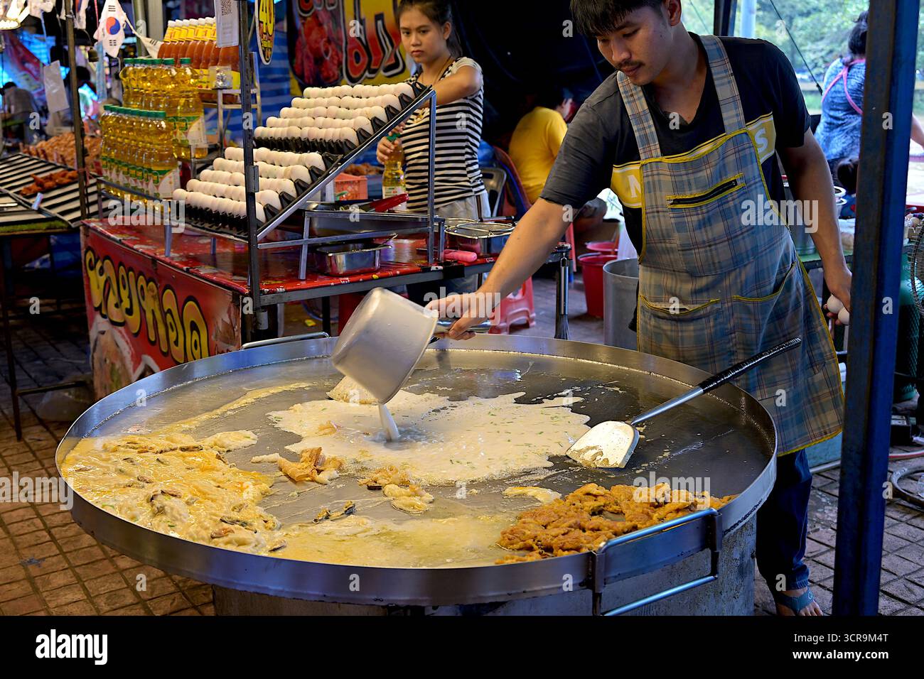 Food vendor cooking Hoi Tod or Thai fried oyster and mussel omelette in ...