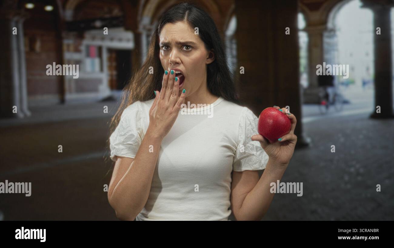 Woman holds shiny red apple with extended right hand near brick ...