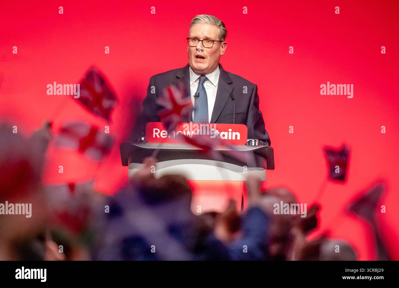 People wave flags as Prime Minister Sir Keir Starmer delivers his ...