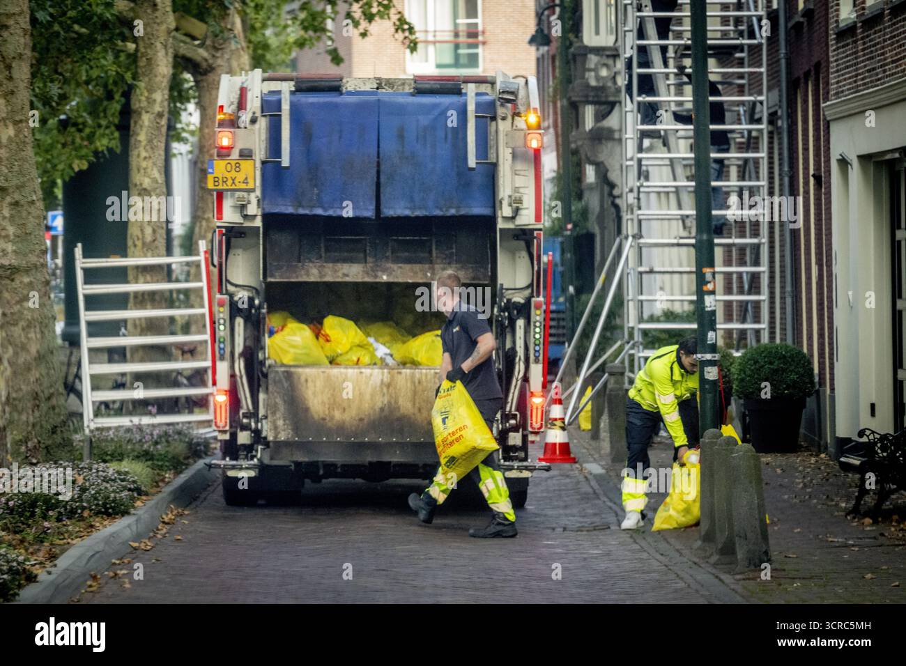 GOUDA - A garbage truck in action with garbage workers loading and ...