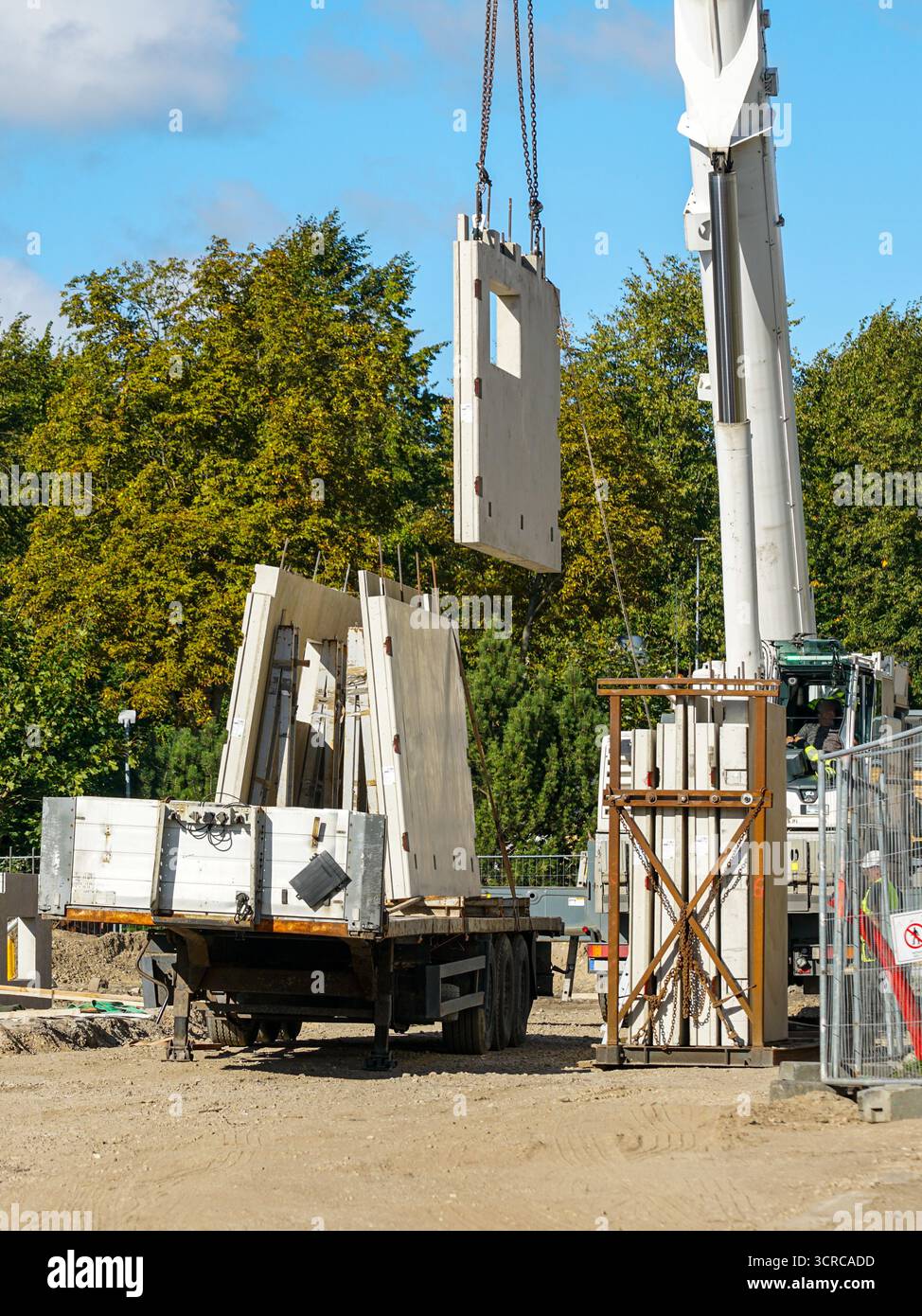 Crane lifting precast concrete wall panel at construction site with ...