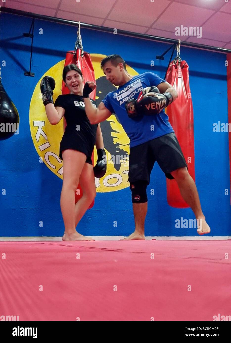 Young female kickboxer playfully flexes her bicep for her impressed ...