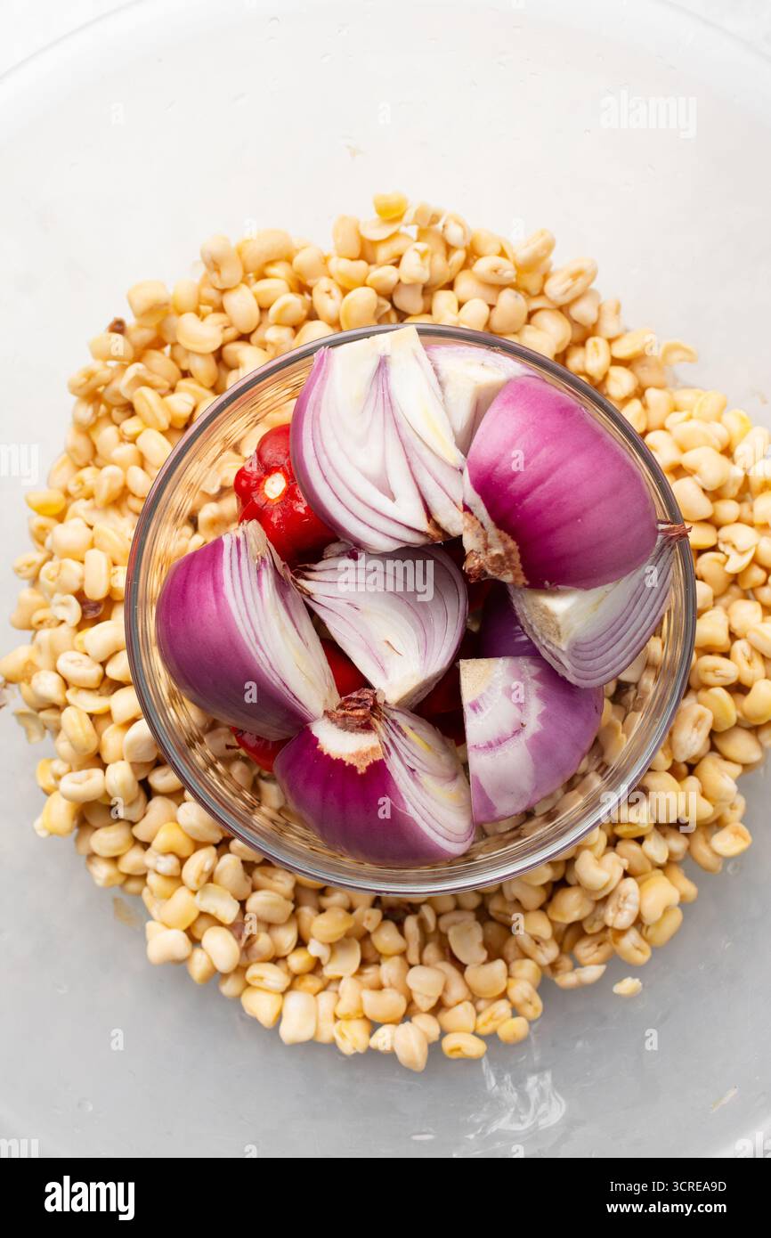Overhead view of onions, pepper and peeled beans in a bowl, Top view of ...