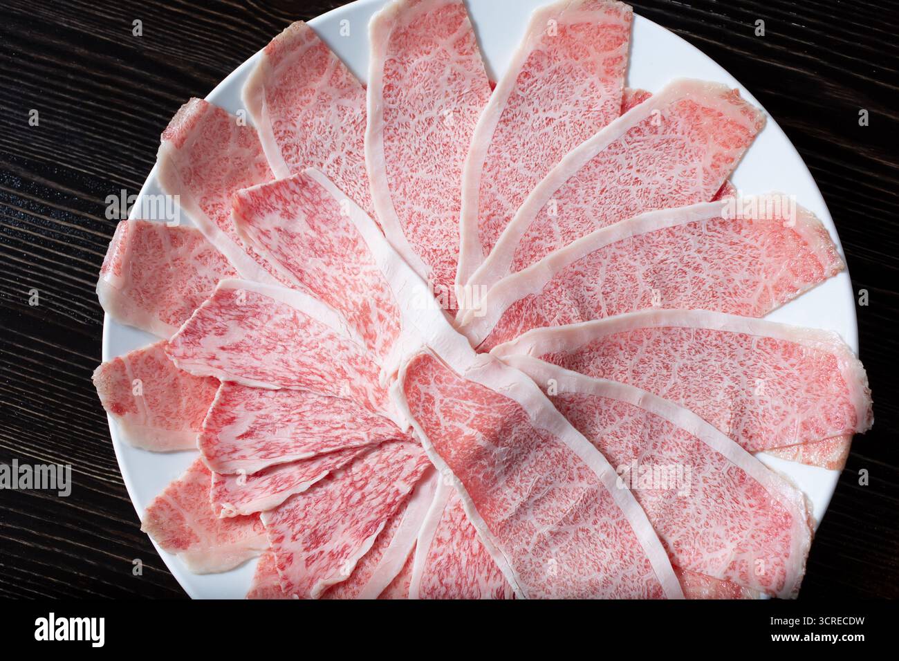 A top down view of a plate of semi-frozen thin slices of A5 Wagyu beef ...