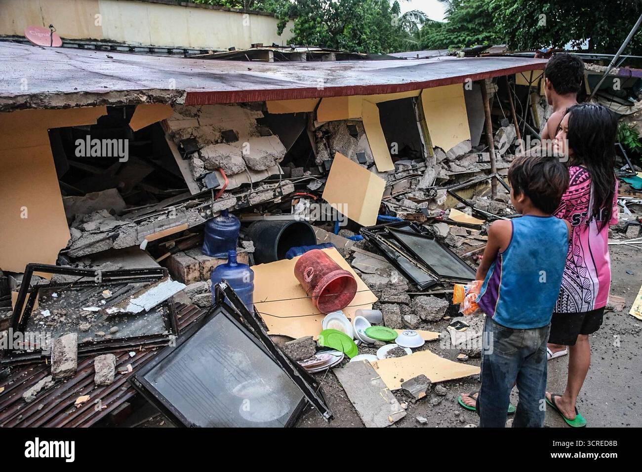 People look at a collapsed building in Bogo City, Cebu province ...