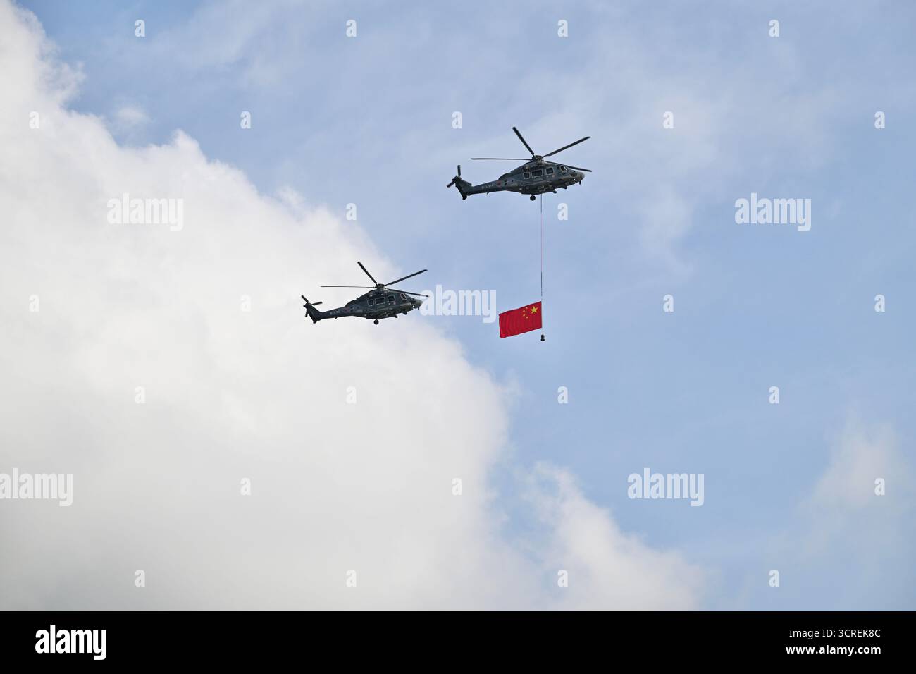 A helicopter carrying the national flag of China fly pass the flag ...