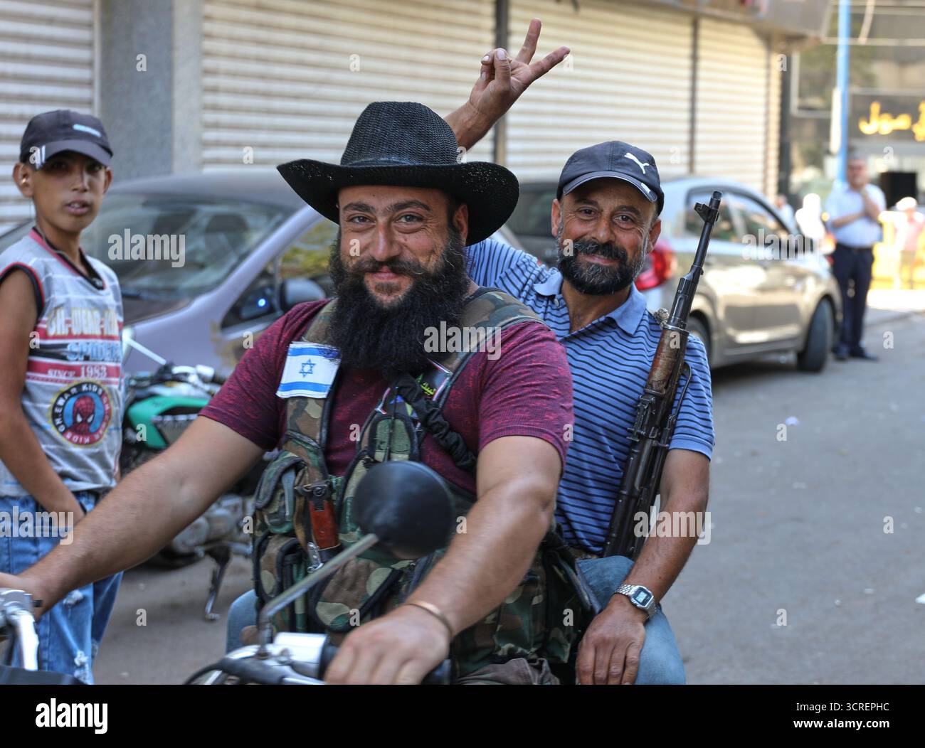 Two Druze gunmen pose for a photo while riding a motorcycle, one ...