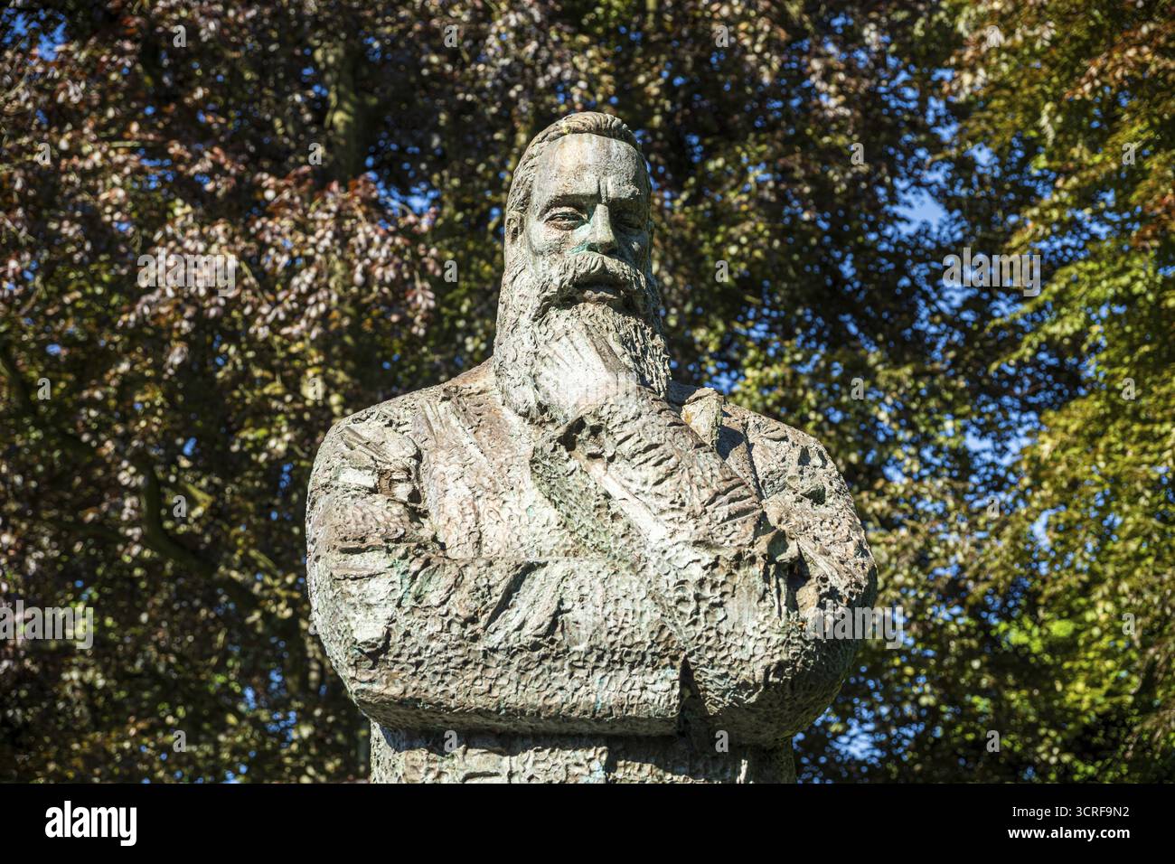 Close-up of a stone statue of a man with a beard, surrounded by trees ...