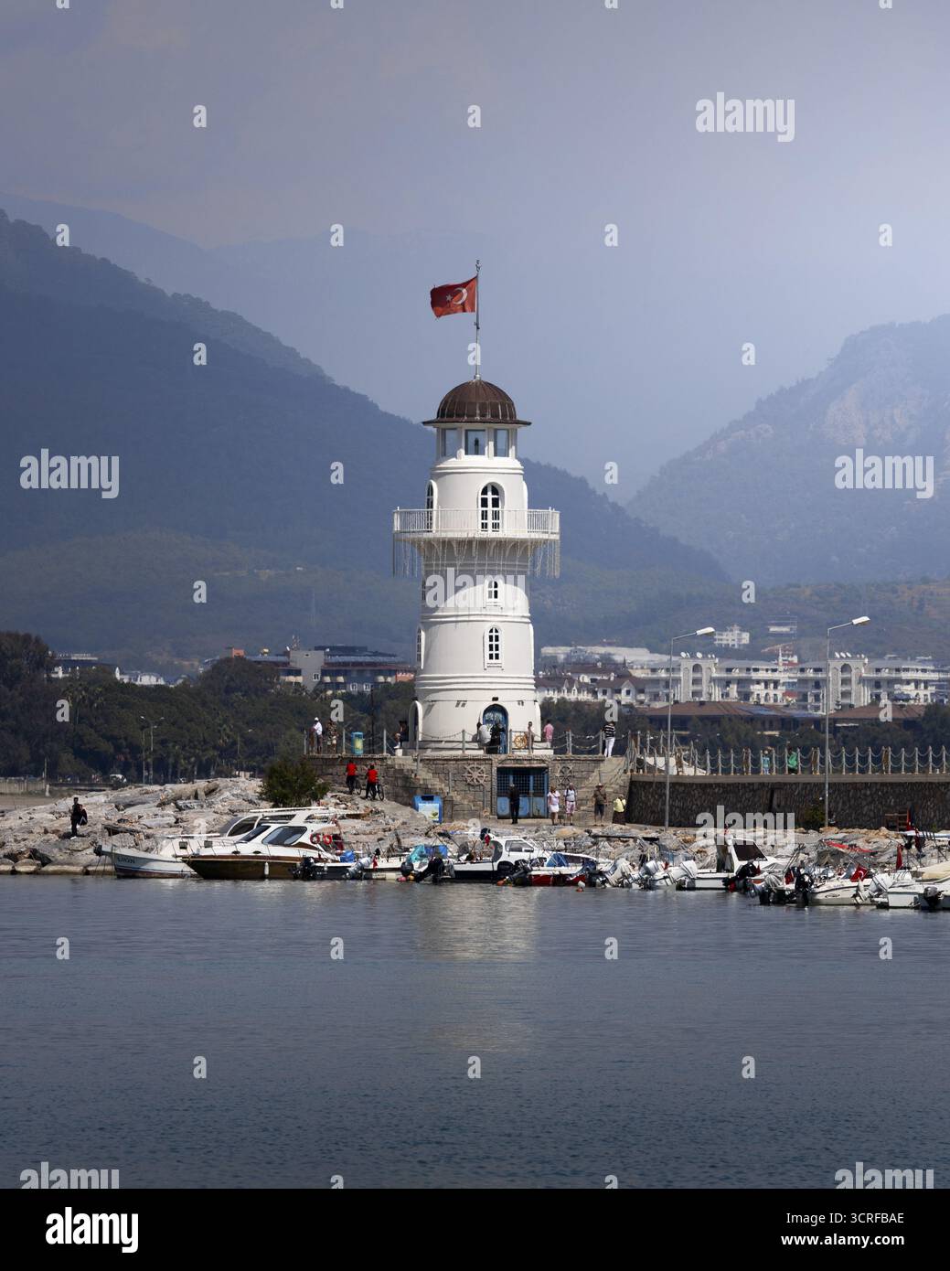 View of a gleaming white lighthouse topped with a Turkish flag stands ...