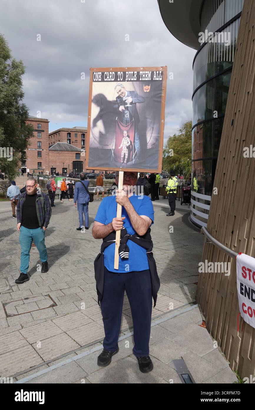 Man at a protest holds a placard reading "One card to rule them all ...