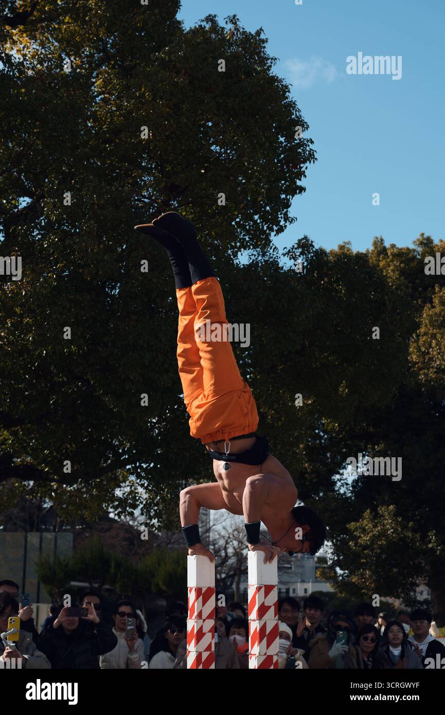 Acrobat performs a vertical handstand on poles during a street show at ...