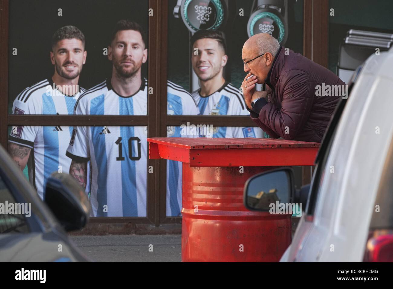 A man smokes next to a poster depicting Argentina's soccer players in ...