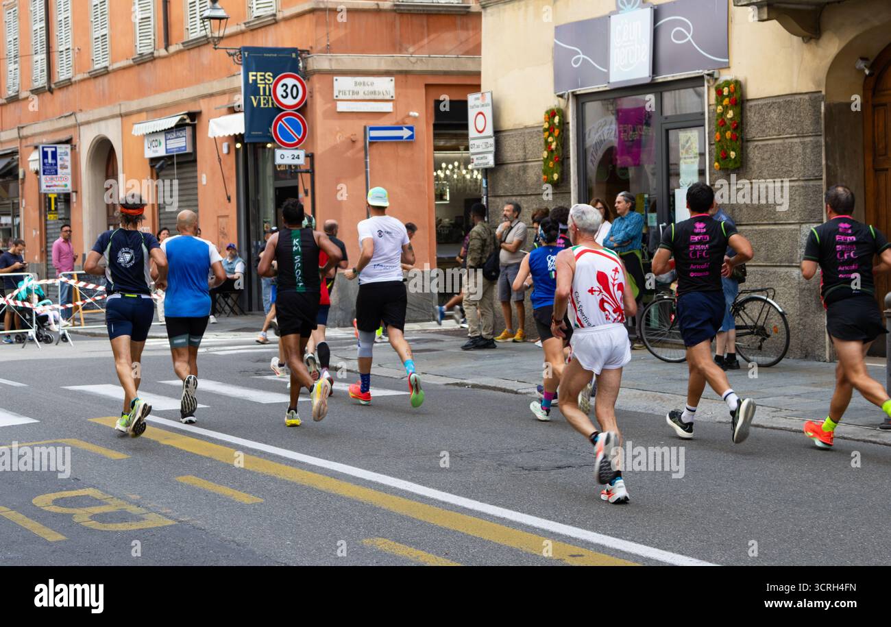 Athletes run marathon together on city street surrounded by colorful ...