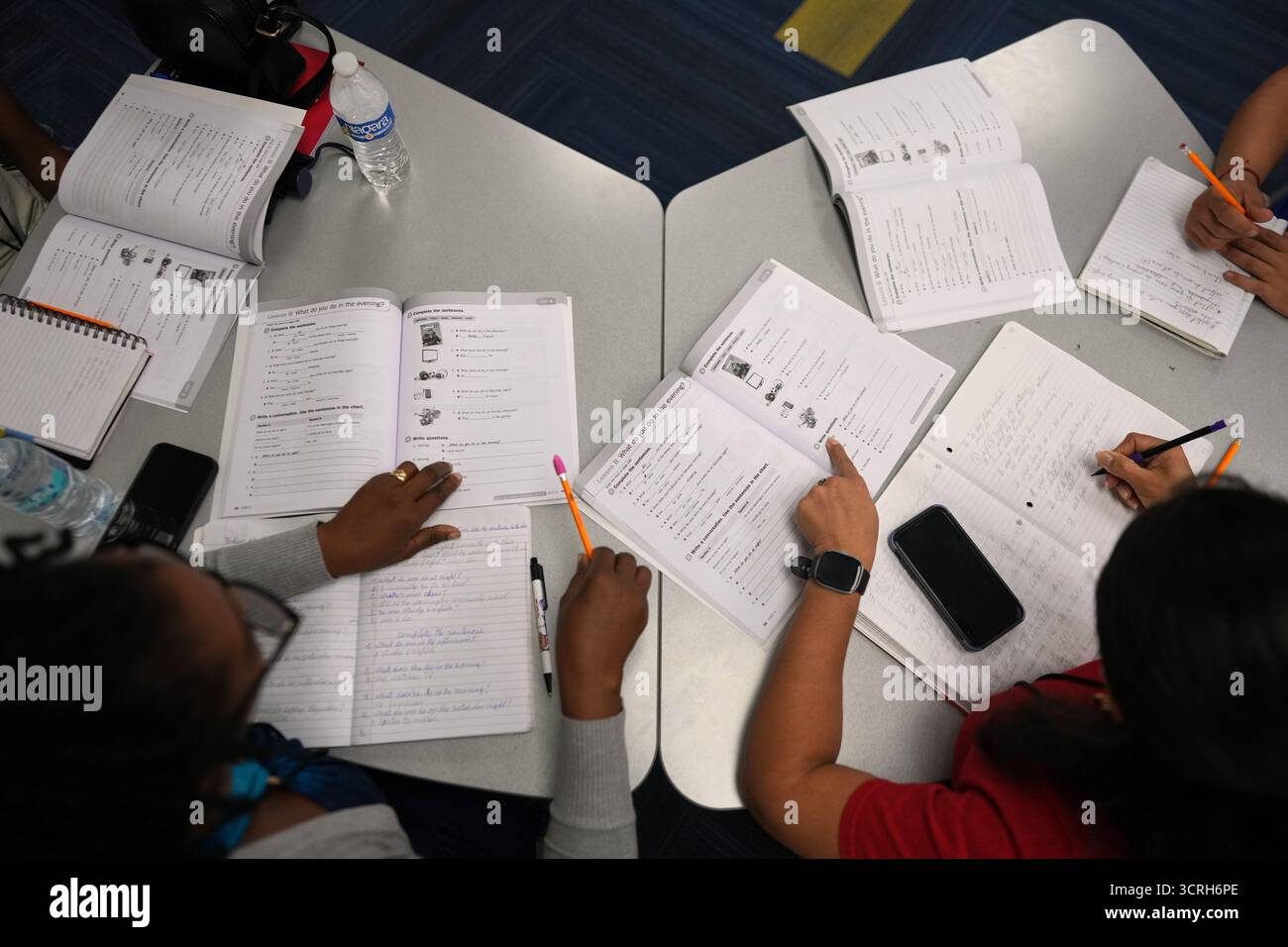 Immigrants trying to learn the English language do a workbook exercise ...
