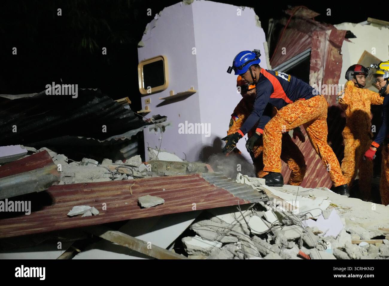 Rescuers check for survivors from the ruins of a collapsed building ...