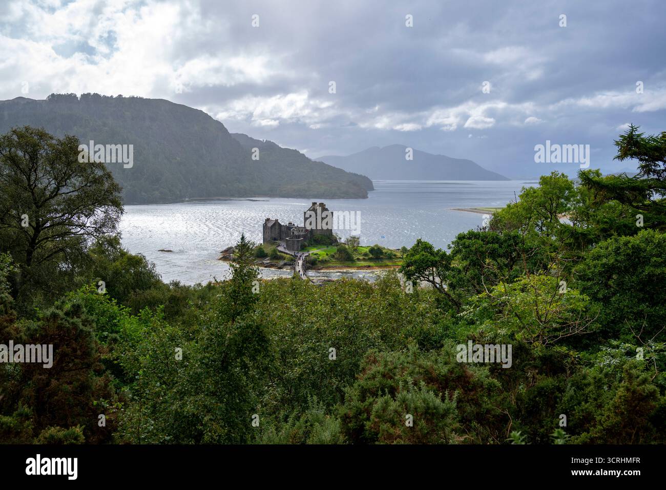 A secluded castle sits on a tiny island, framed by lush forest and ...