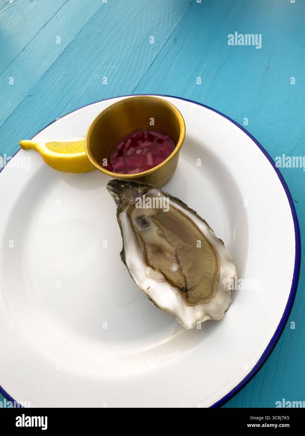 Single opened oyster served with fresh lemon slice and tangy sauce on ...