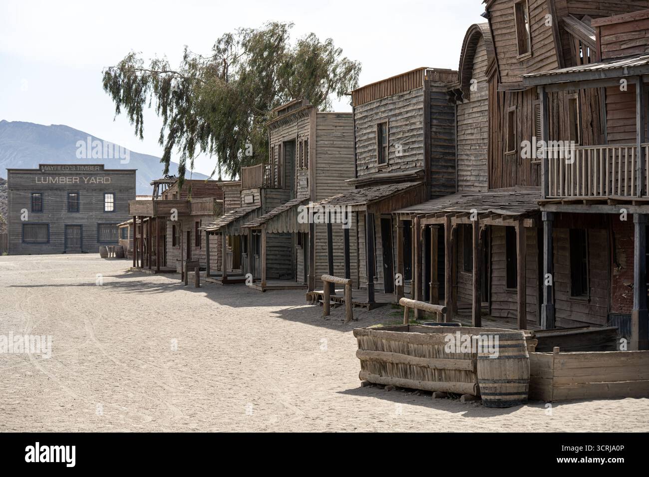 A deserted western town with wooden buildings and a sandy street ...