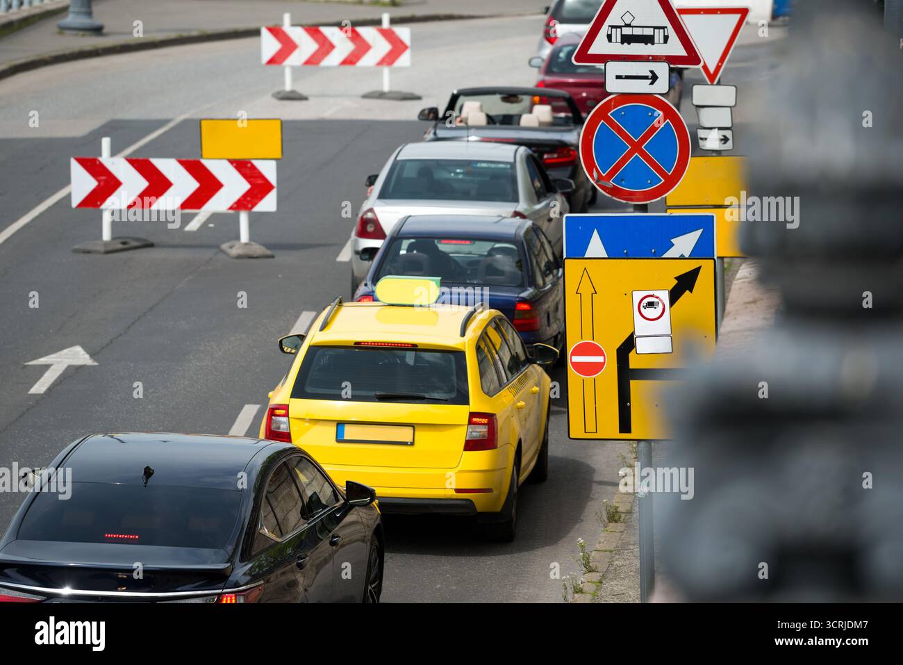 Cars standing in a queue, lot of road signs Stock Photo - Alamy