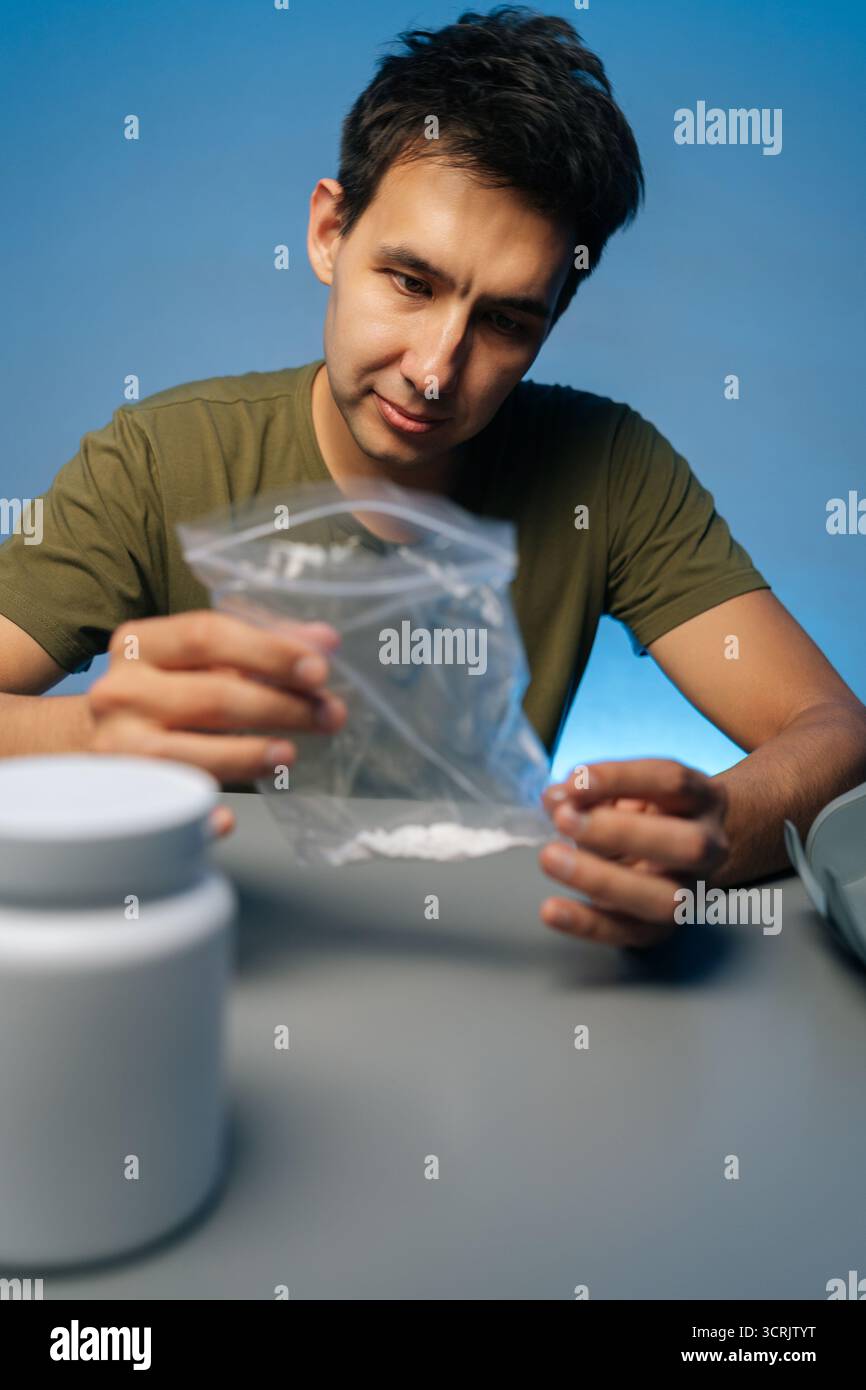 Vertical portrait of drug dealer male preparing dose of cocaine or ...