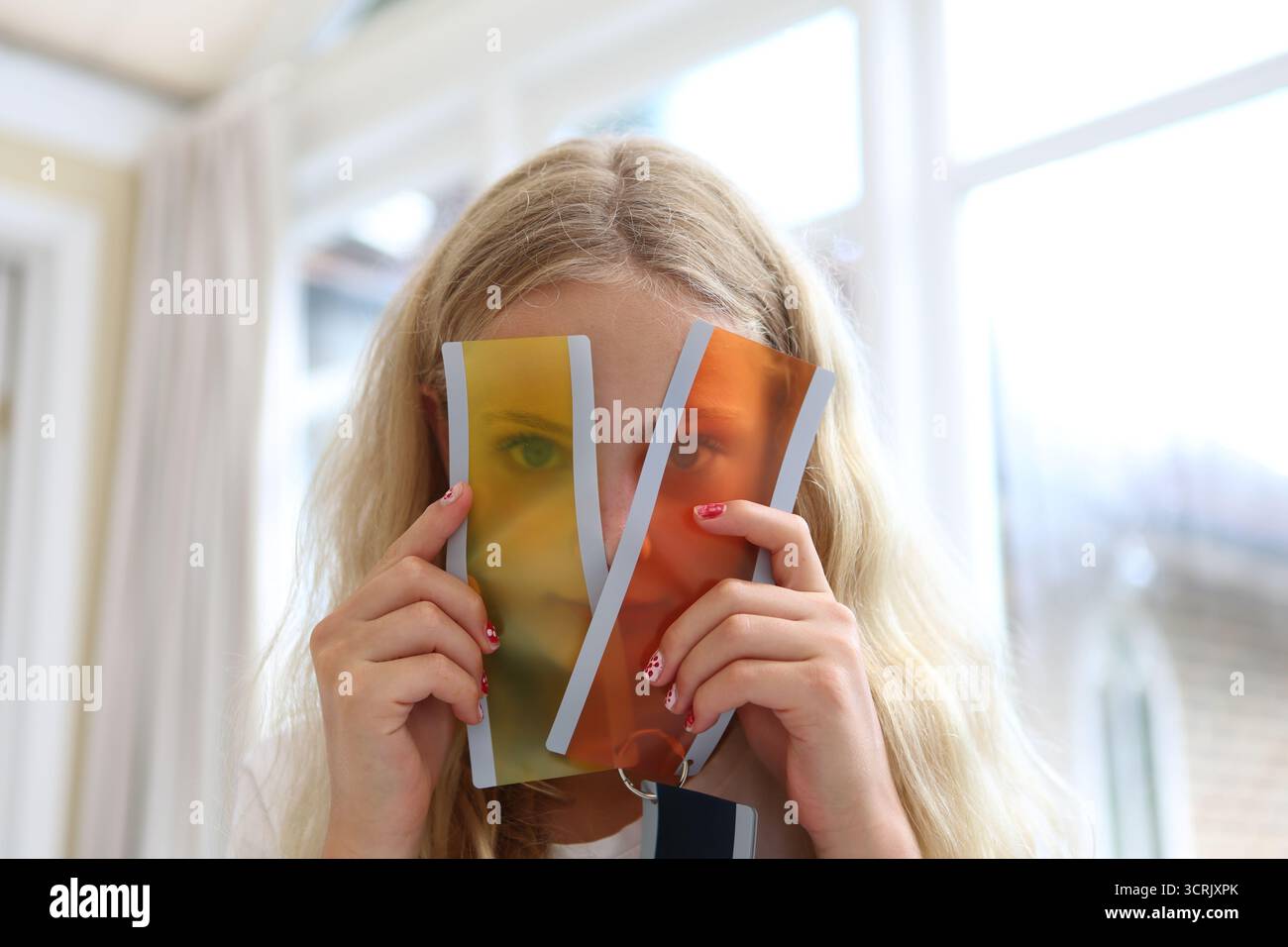 Girl with coloured acetate dyslexia reading aids held in front of eyes ...