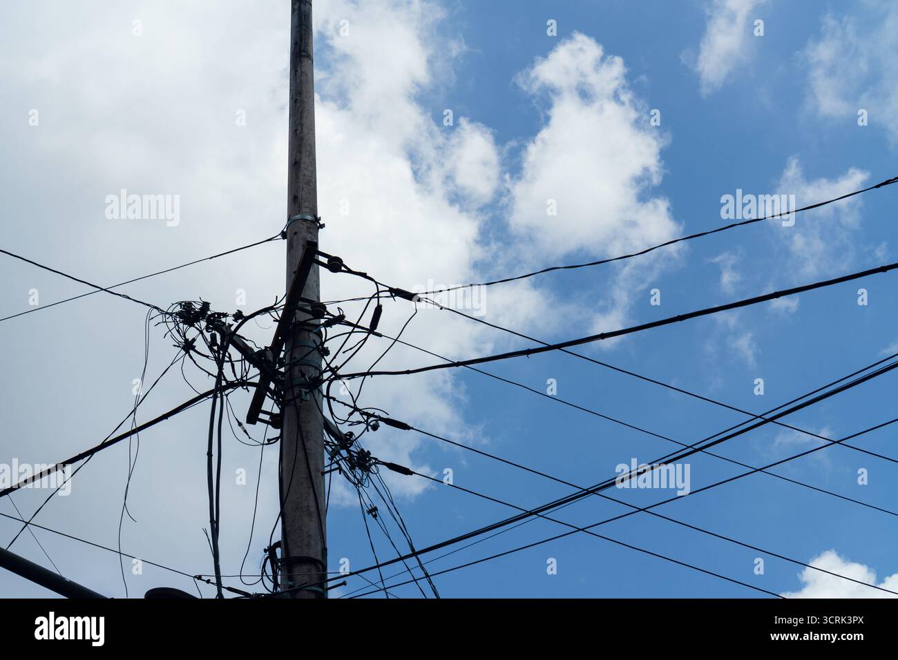 Messy and tangled electrical power lines on a utility pole against a ...