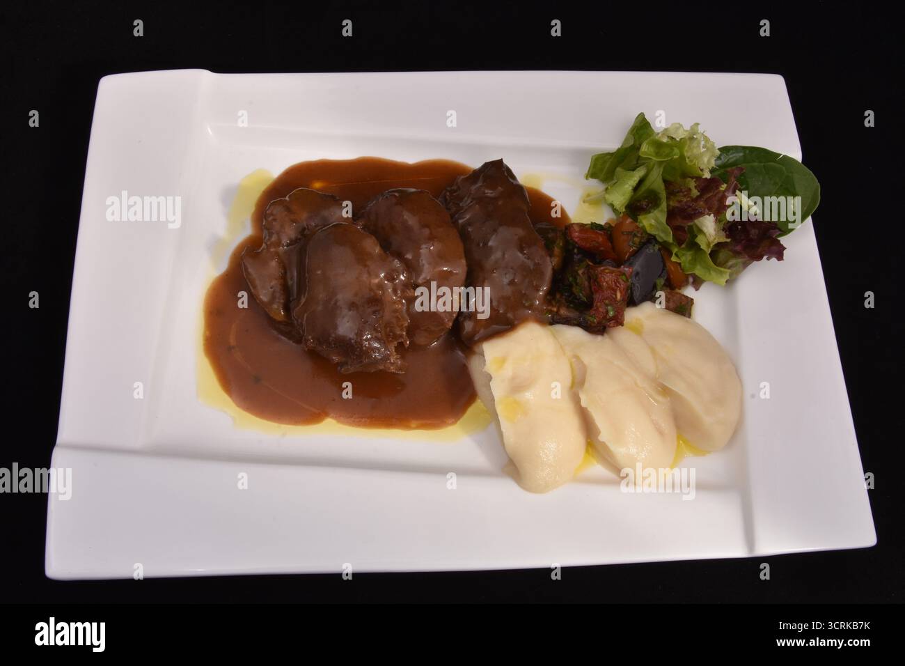 a portion of liver with sauce, served with a creamy puree and a green ...