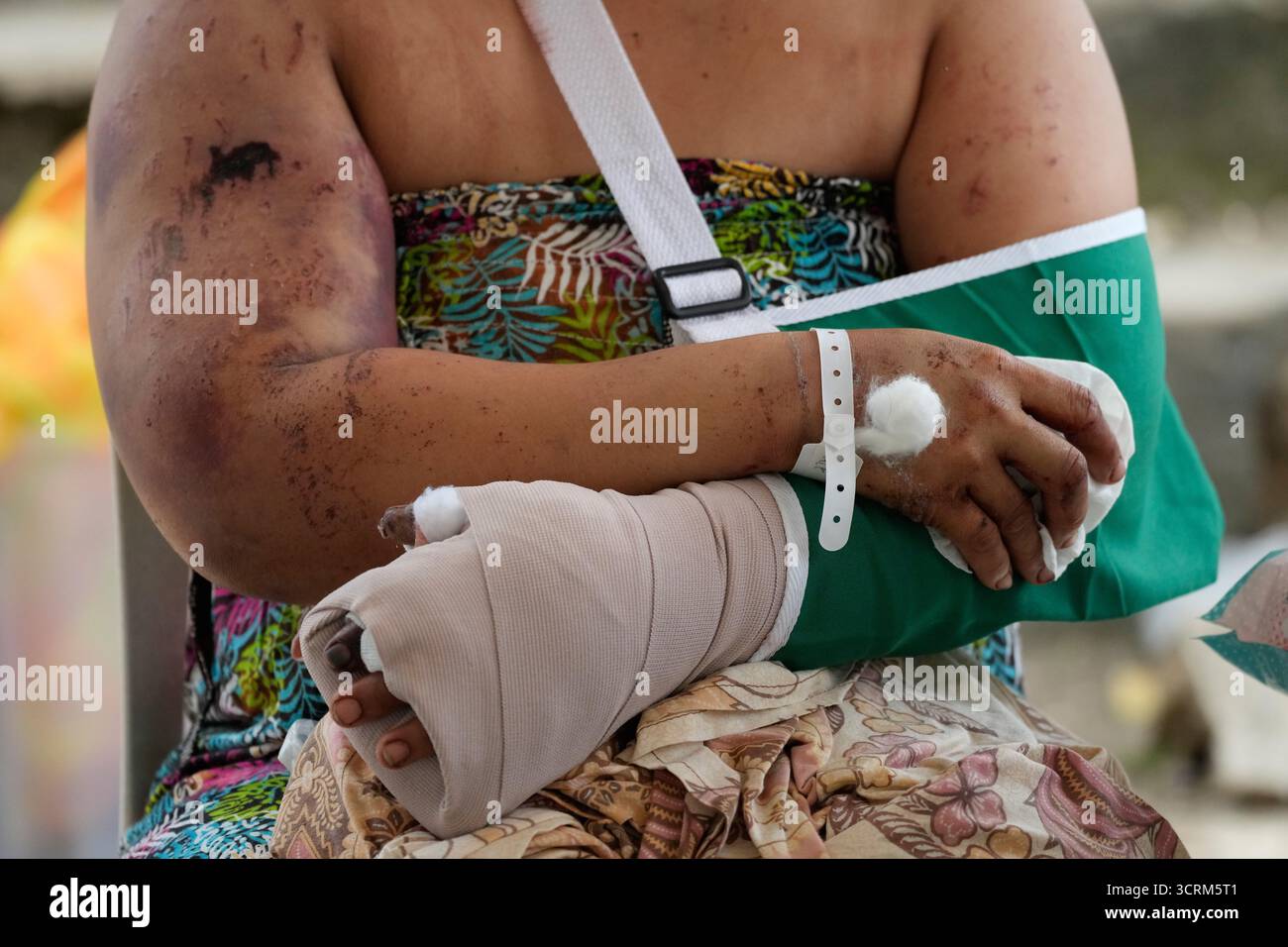 Earthquake survivor Jesiel Malinao sits beside the coffins of her two ...