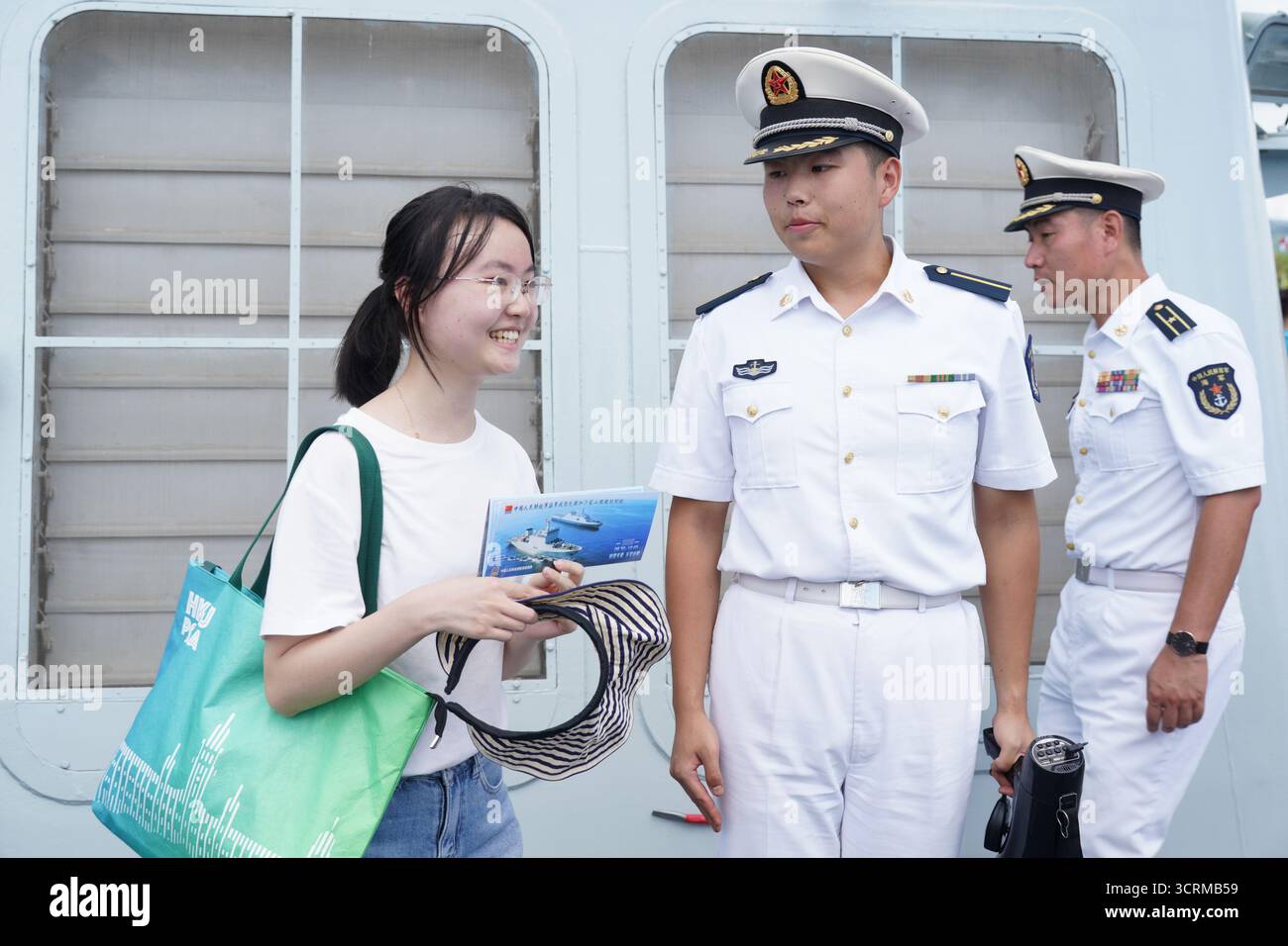 A girl take photos with PLA officers on the deck of the Chinese PLA ...