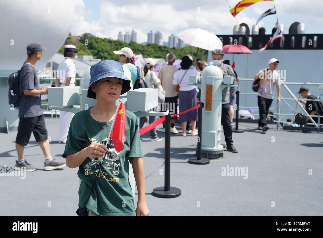 A boy take photos with PLA officers on the deck of the Chinese PLA Navy ...
